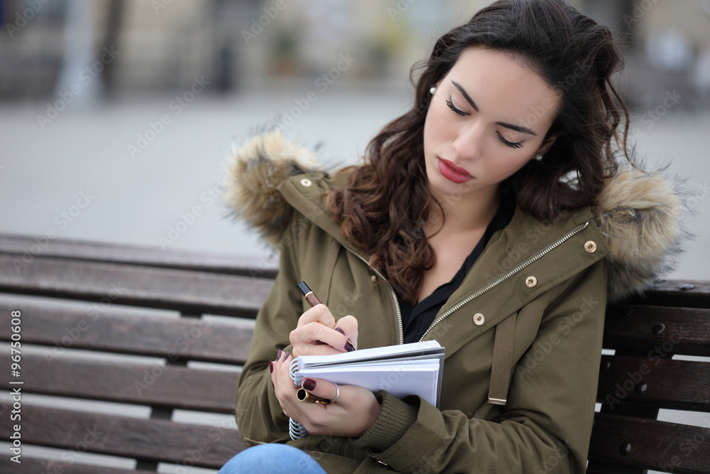 Young girl sitting on a bench writing in her diary Stock Photo | Adobe ...