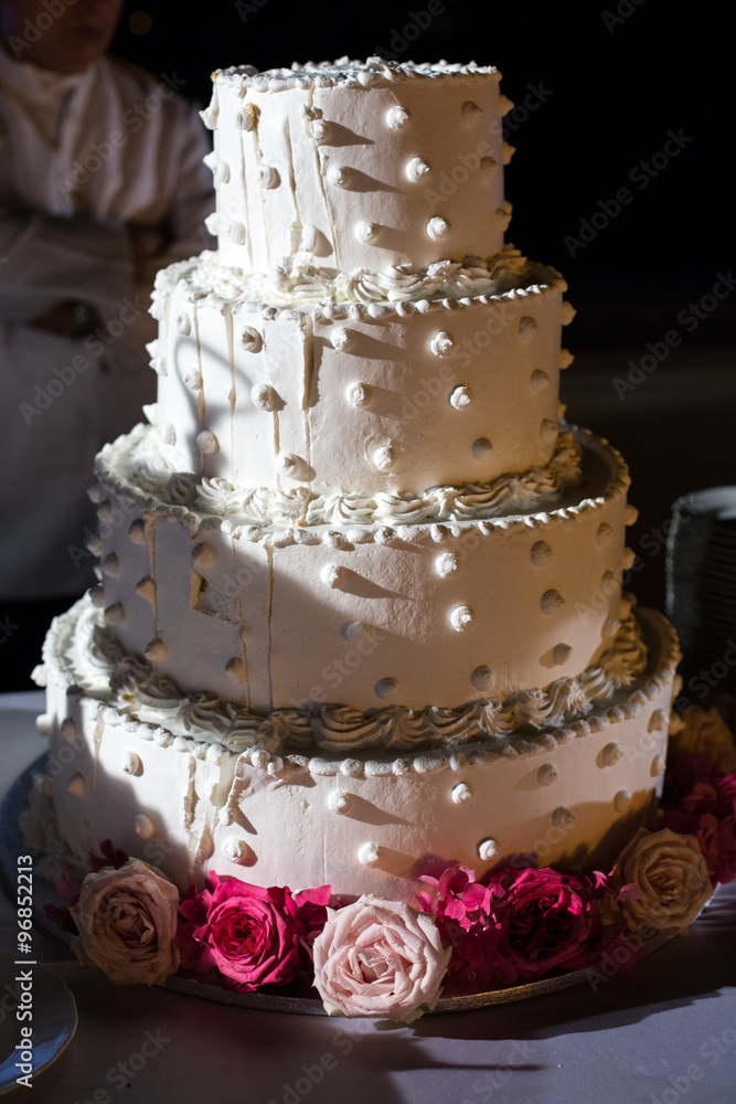 Foto Stock Torta di nozze a piani ricoperta di panna e rose colorate ...
