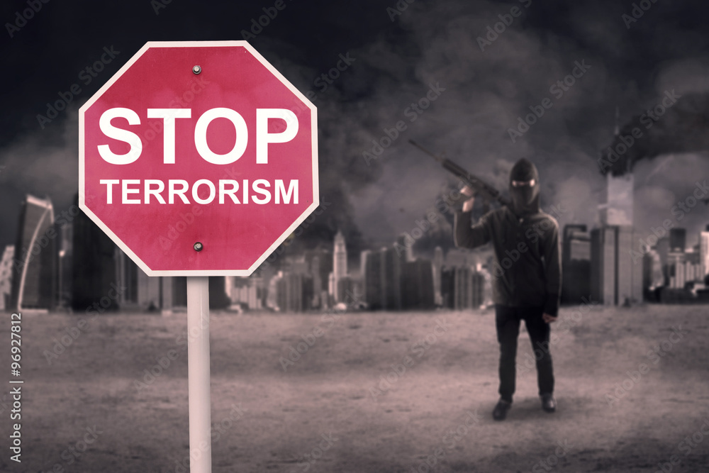 Road sign with text stop terrorism and man with rifle damaged city in ...