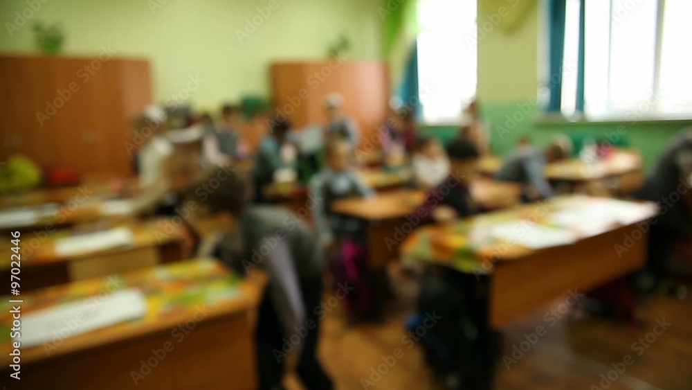 blurred background group of kids in classroom at a school desk is ...