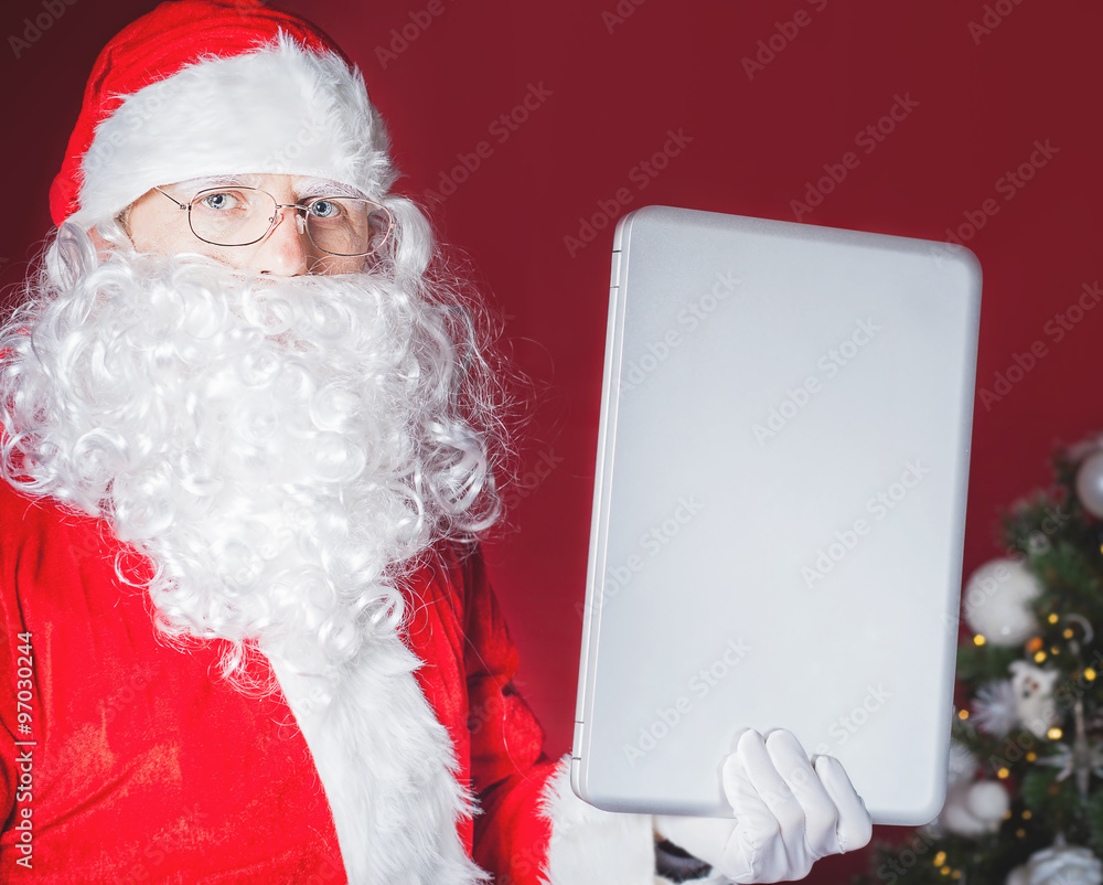 Santa Claus holding a laptop computer Stock Photo | Adobe Stock