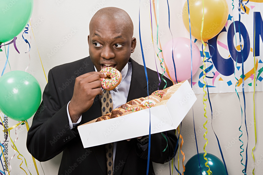 Businessman secretly eating doughnuts Stock Photo | Adobe Stock
