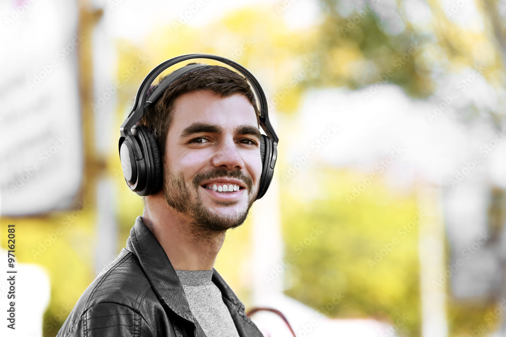Young man listening to music and walking along the street Stock Photo ...