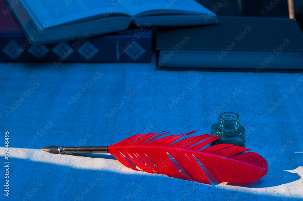 Red quill pen and black inkwell on a papyrus sheet enlightened by a ...