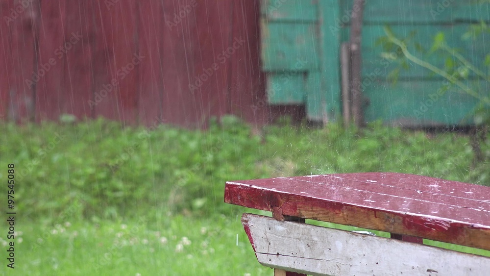 Heavy rain water drops fall and splash on wooden outdoor surface ...