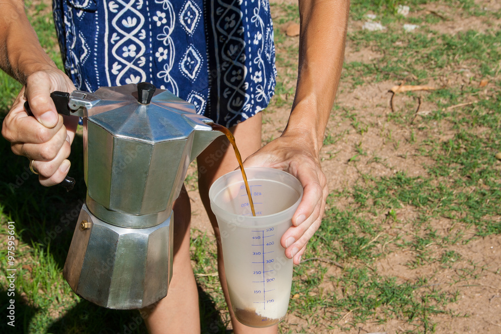 Woman pouring coffee in a bowl with a Moka pot at campsite. Stock Photo ...