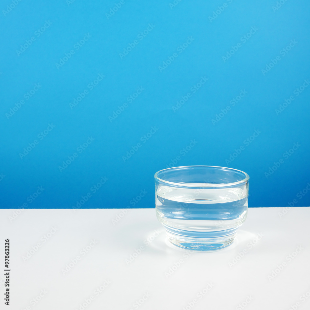 The small glass of pure water on a white table. Stock Photo | Adobe Stock