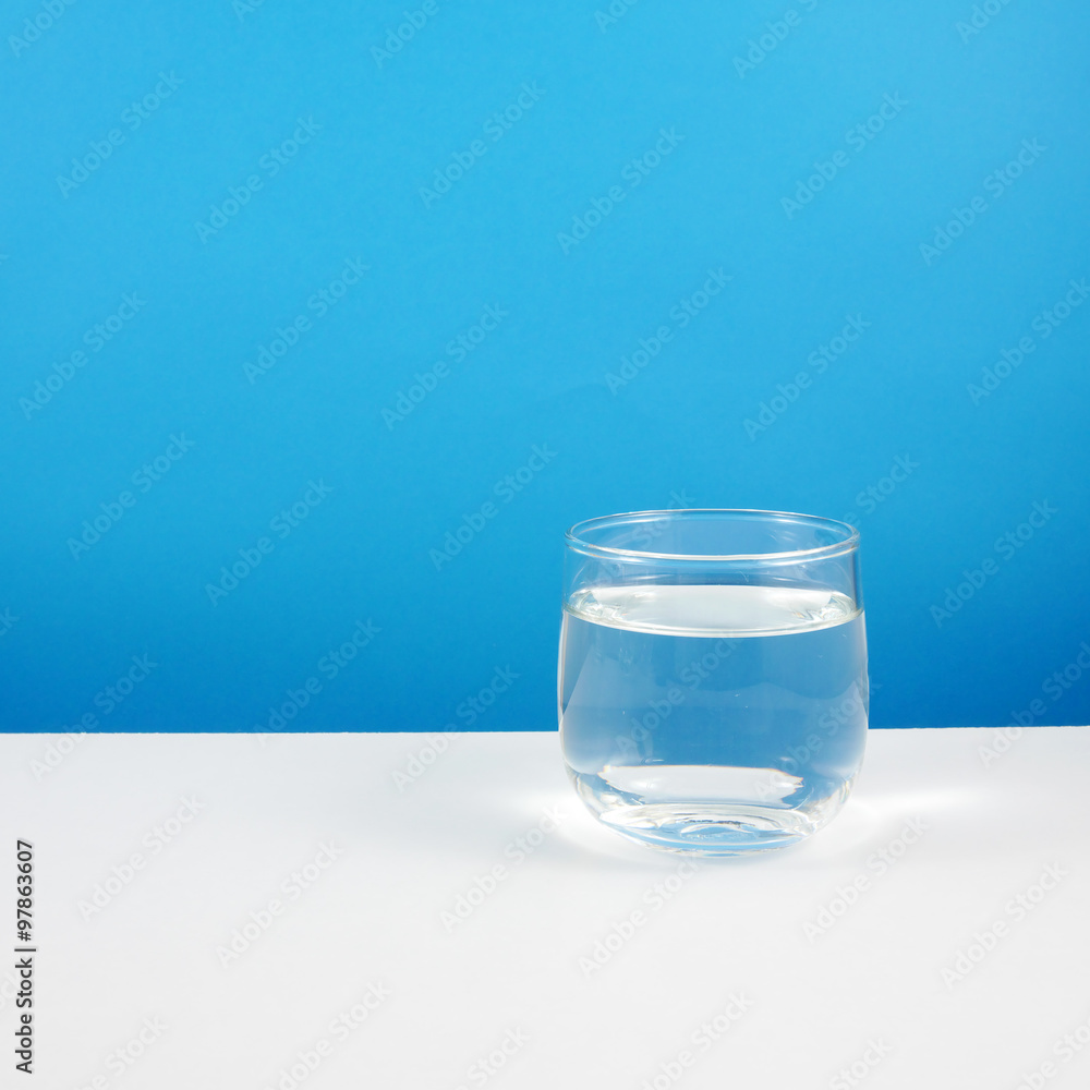The small round glass of pure water on a white table. Stock Photo ...