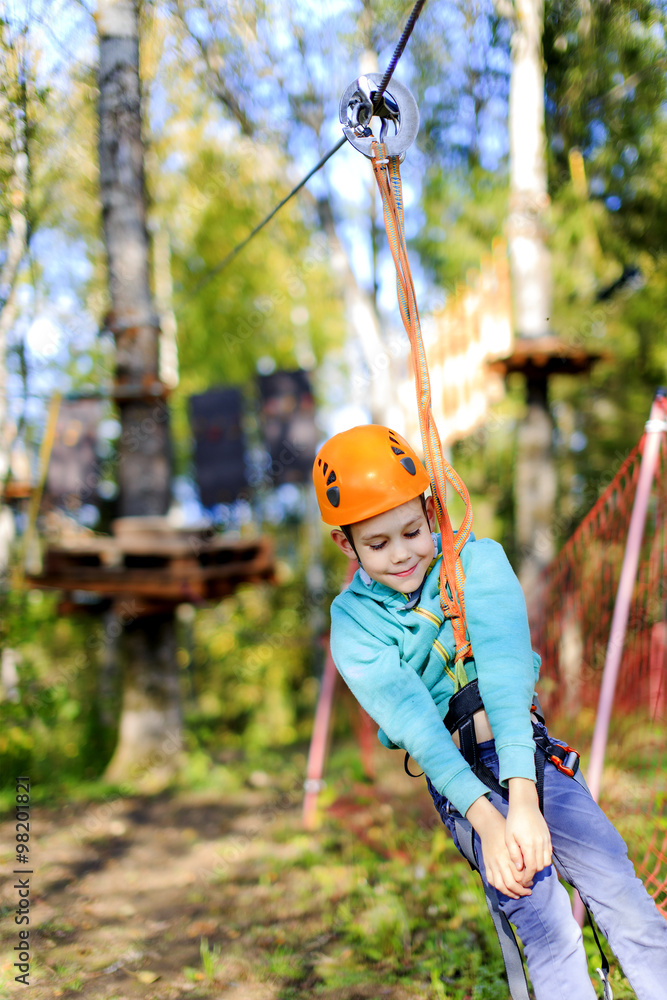 happy boy slides on the rope in the rope park. child enjoys sliding ...