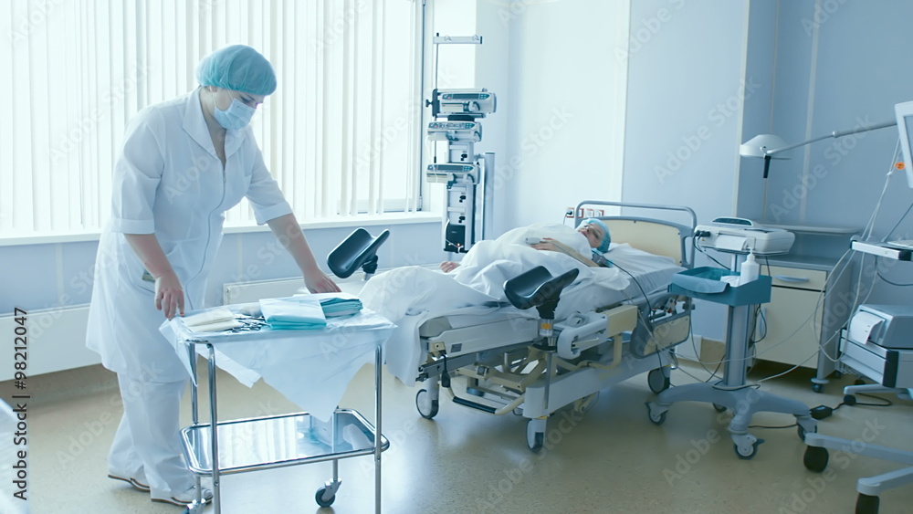A doctor is preparing a pregnant woman lying in the medical bed in the ...