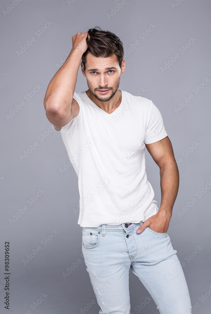Handsome man touching his hair. Fashion model posing in white t- Stock ...