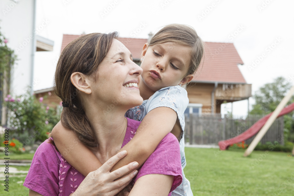Smiling mother carrying daughter piggyback in garden Stock Photo ... Smiling mother carrying daughter piggyback in garden Stock Photo ...