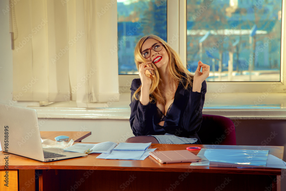 Portrait of a pretty secretary sitting at her desk and smiling a Stock ...
