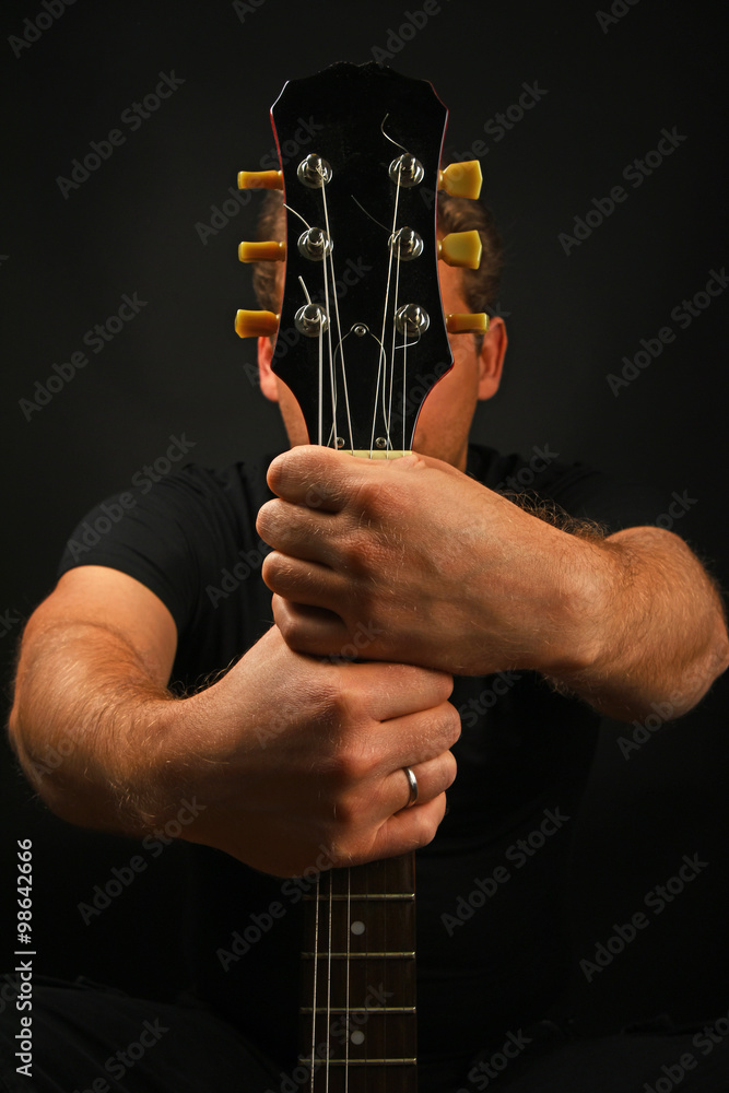 Man holding guitar neck with two hands isolated on black foto de Stock ...