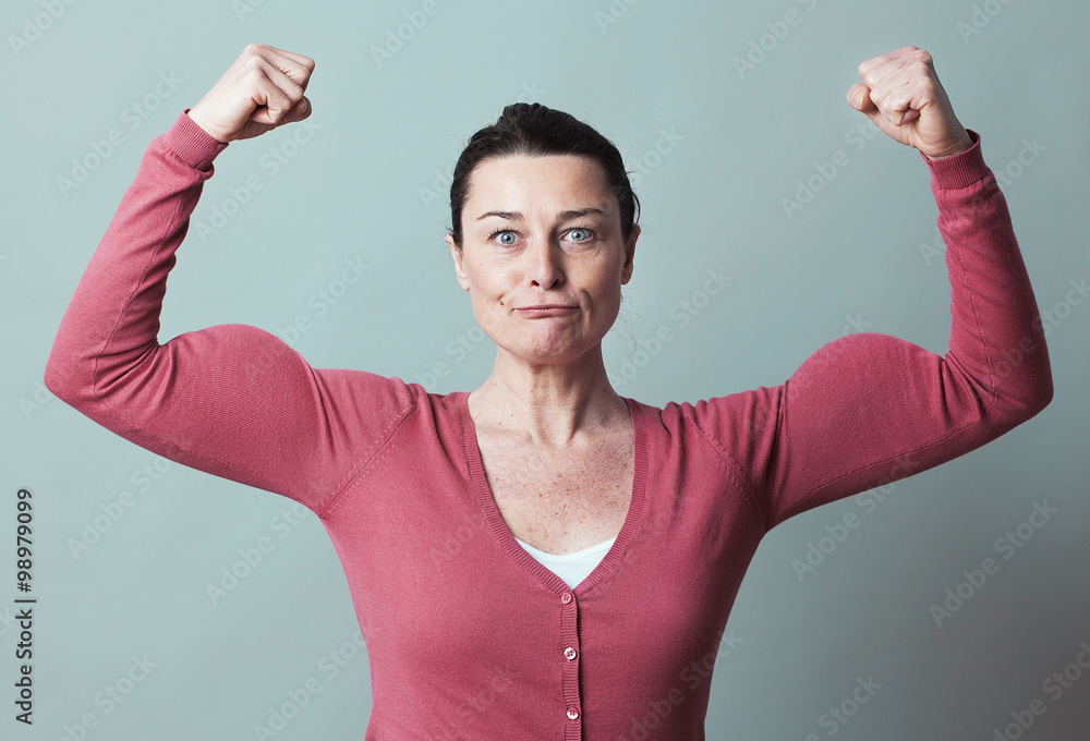muscle concept - smiling 40s woman lifting her muscles up for metaphor ...