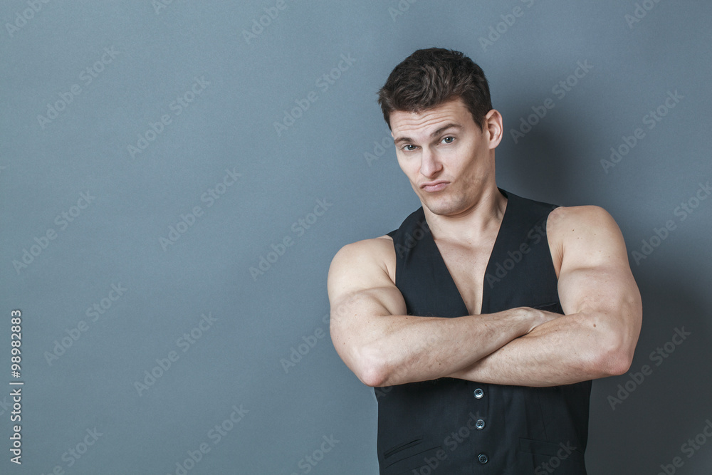 muscle concept - dubious young man crossing his big muscular arms ...