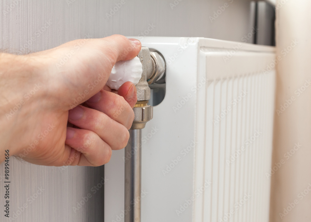 Radiator adjustment closeup. Man's hand adjusting radiator temperature ...