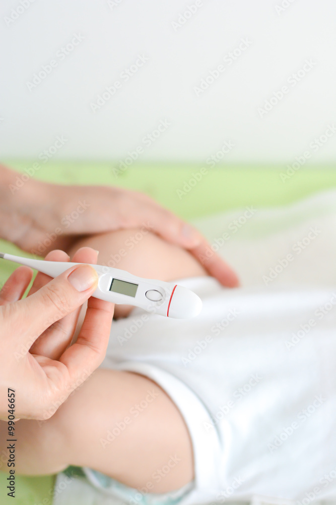 Checking baby temperature which indicates high fever on thermometer ...