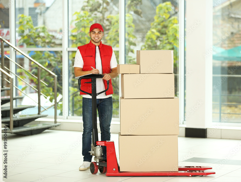 Delivery concept - postman in red uniform with parcels on dolly Stock ...