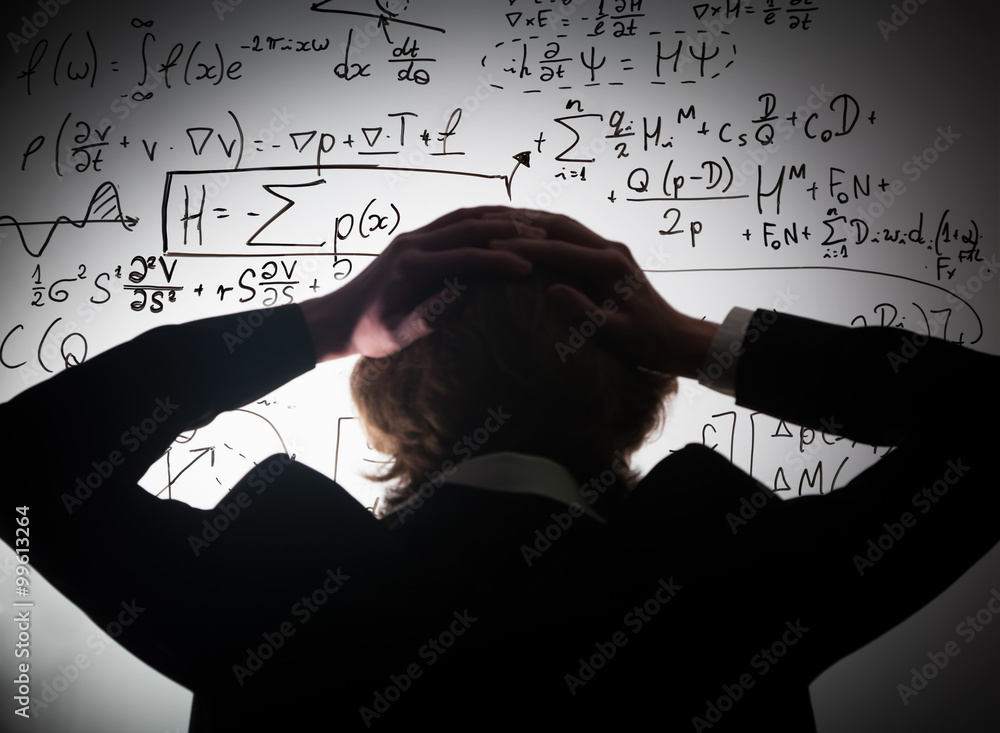 Student holding his head looking at complex math formulas on whiteboard ...