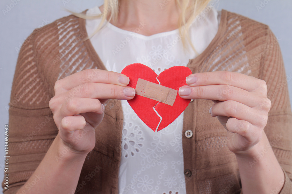 Woman holding broken heart fixed by plaster close up. Feelings and ...