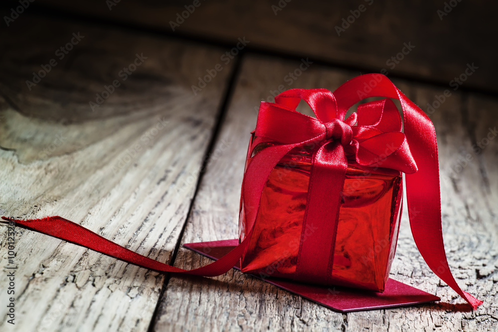 Red gift box tied with a scarlet ribbon with a bow on the old wo Stock ...