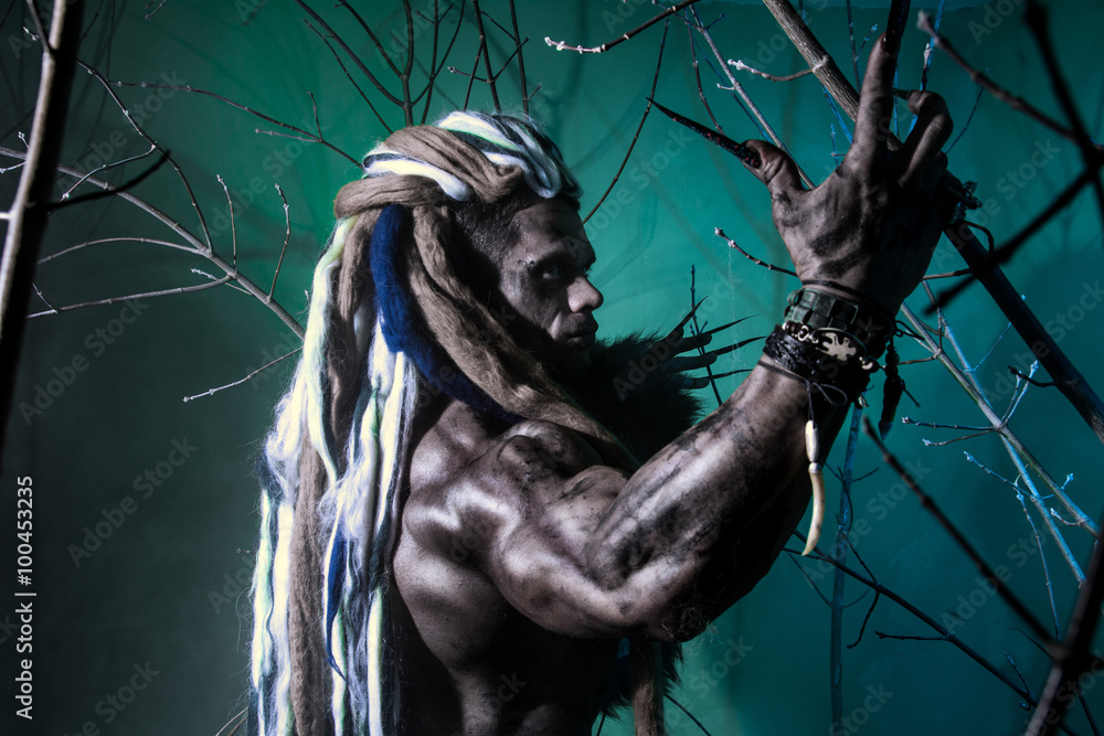 Portrait muscular werewolf with dreadlocks among the branches of Stock ...