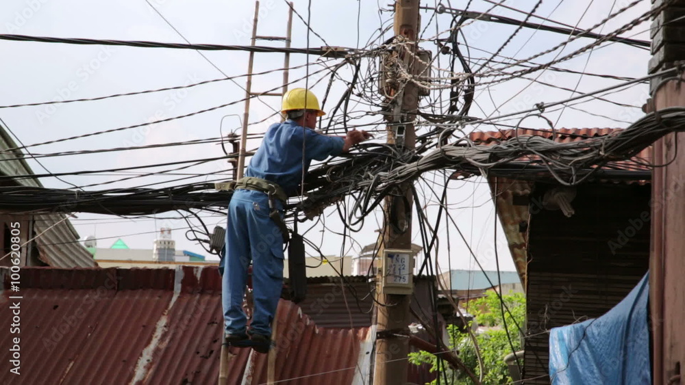 electrician fixing, repairing messy electric cables in hanoi slums ...