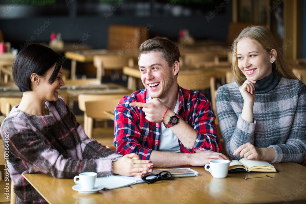 guy and two girls having fun at the cafe. The boy and two girls sitting ...