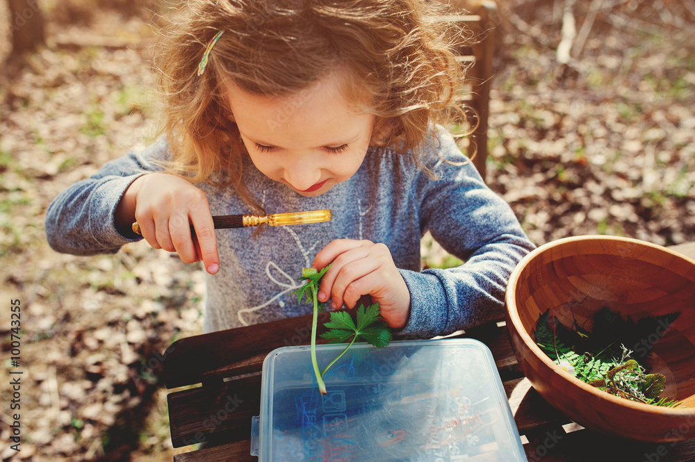 child girl exploring nature in early spring, looking at first sprouts ...