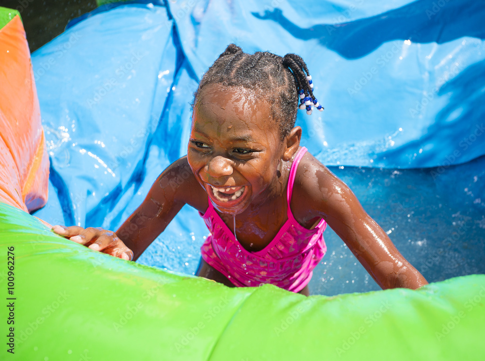 Smiling little girl playing outdoors on an inflatable bounce house ...