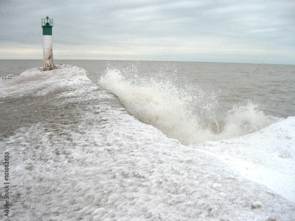 Waves crash against a pier covered in ice and snow. Stock Photo | Adobe ...