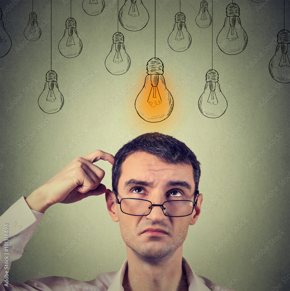 Portrait thinking man in glasses looking up with light idea bulb above ...