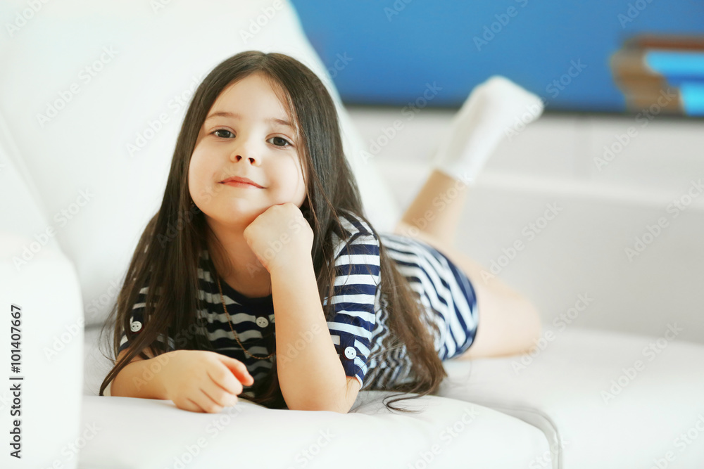 Beautiful little girl lying on sofa in the room Stock Photo | Adobe Stock