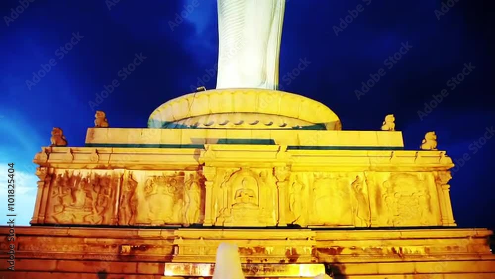 Tilt up shot of a statue of Lord Buddha lit up at night, Hussain Sagar ...