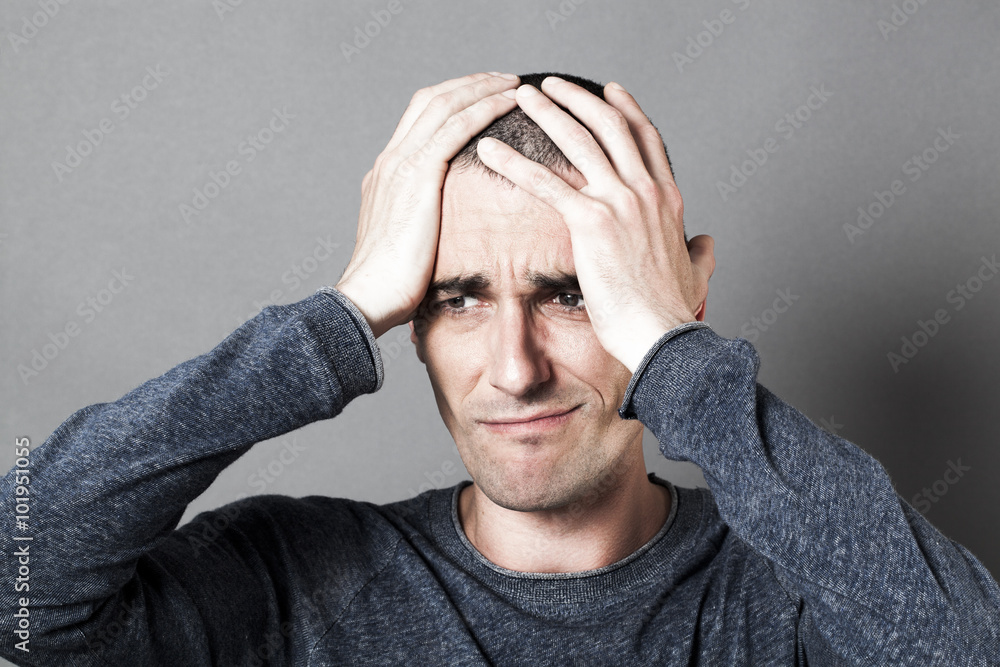 male despair concept - sad young dark man frowning, holding his head ...