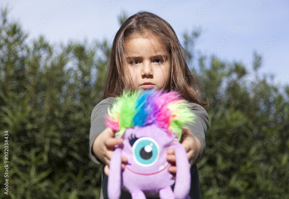 Foto de Niña enfadada con peluche de colores do Stock | Adobe Stock