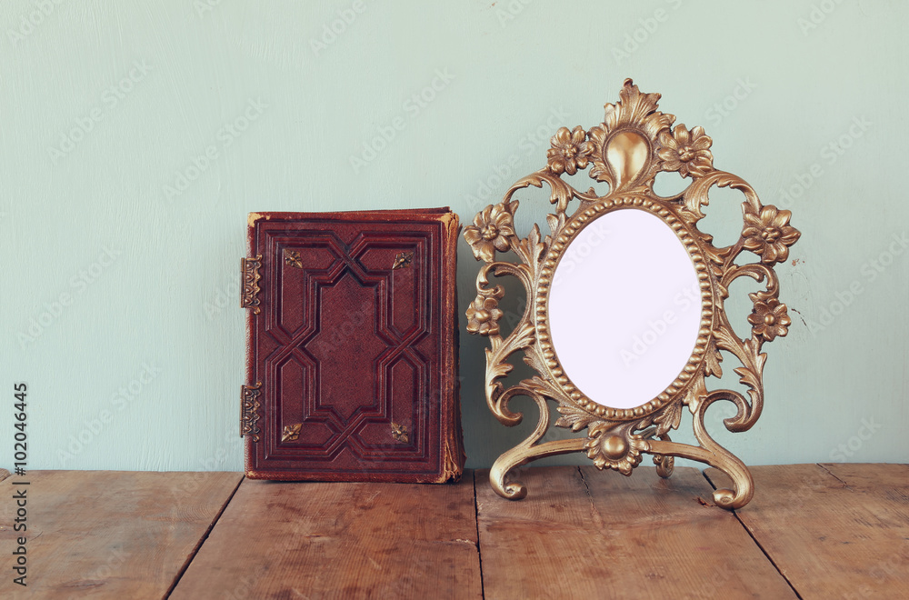 Antique blank victorian style frame and old book on wooden table. retro ...