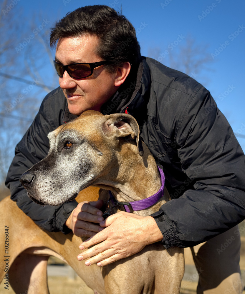 Handsome man holding his great Dane protectively both looking left ...