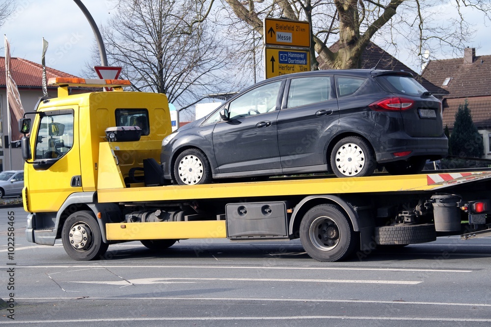 Gelber Abschleppwagen transportiert einen PKW Stock Photo | Adobe Stock