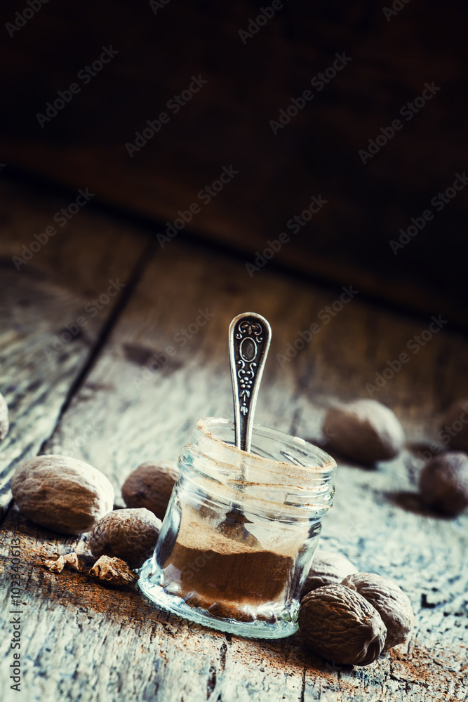 Ground nutmeg in a jar and whole nuts on an old wooden backgroun foto ...
