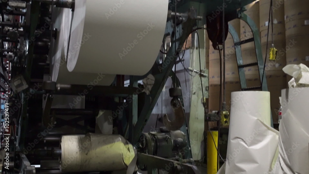 Tilt up shot of the large paper rolls that feed into an industrial ...