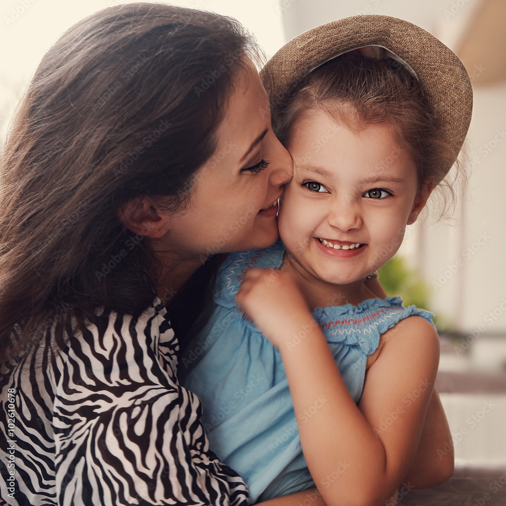 Happy mother cuddling and kissing her cute kid girl in hat. Tone Stock ...