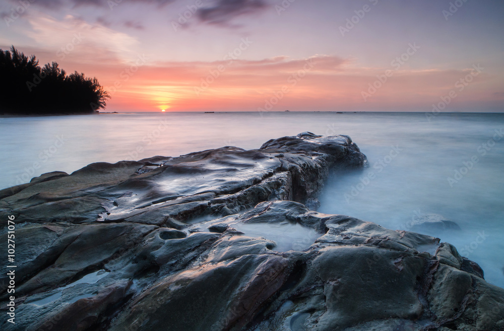 orange sunset with giant rock on the beach. slow shutter speed image ...