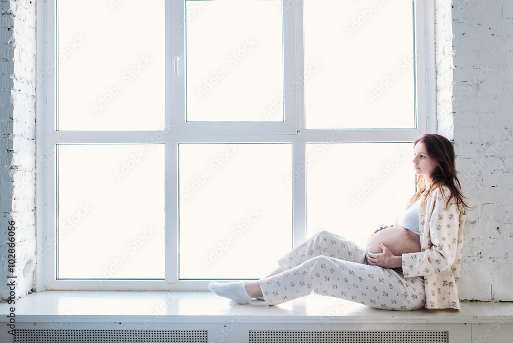 Pregnant girl sitting on the window sill Stock Photo | Adobe Stock