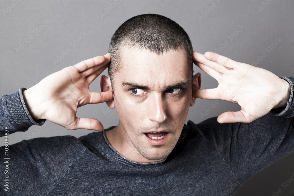 noise and hearing concept - surprised young man plugging his ears to ...