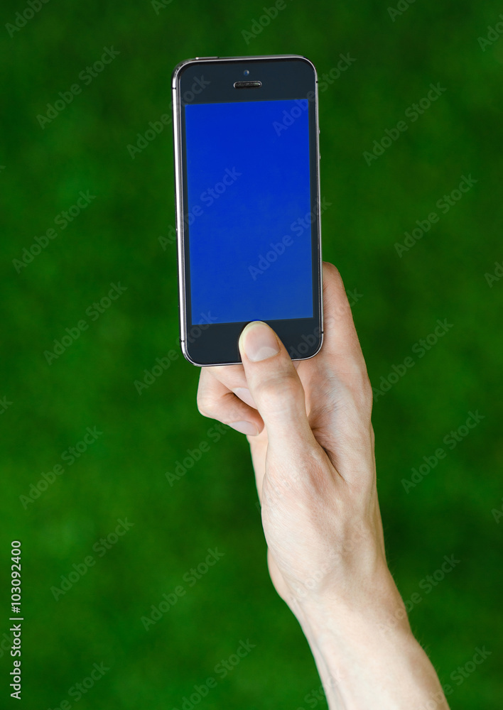 Human hand holding a modern mobile phone with a blue screen on a ...
