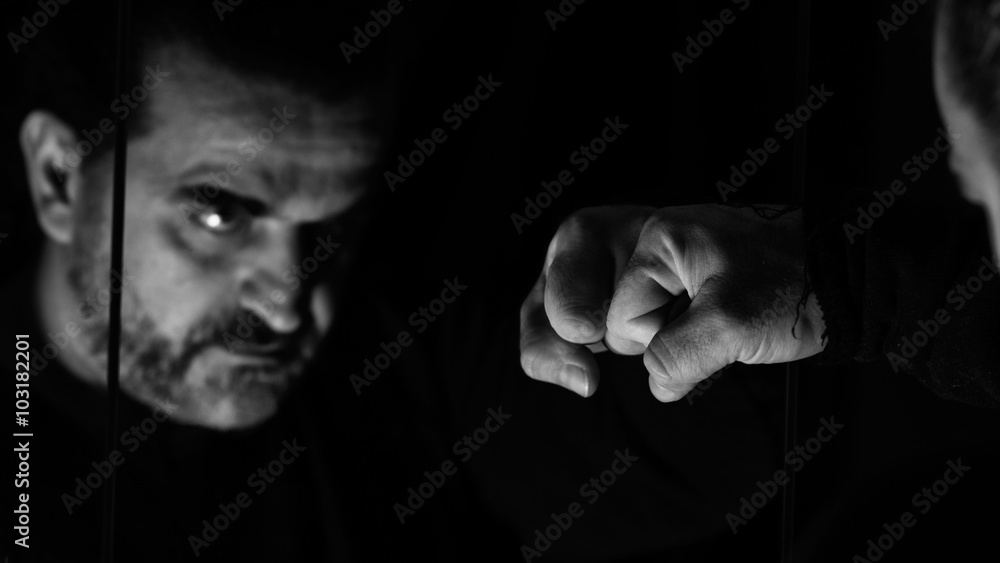 Angry man fist punching mirror and his reflection, monochromatic image ...