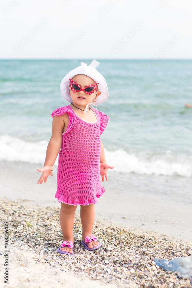 The child, a little girl posing on the beach, small model on the beach ...