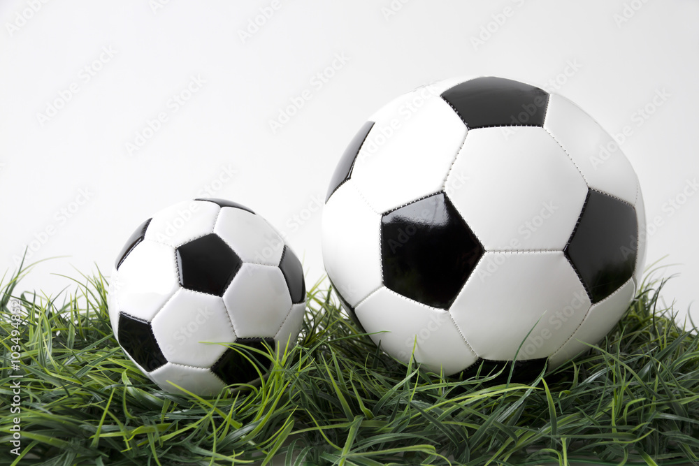 Picture shows two footballs on a green field. Tabletop with white ...